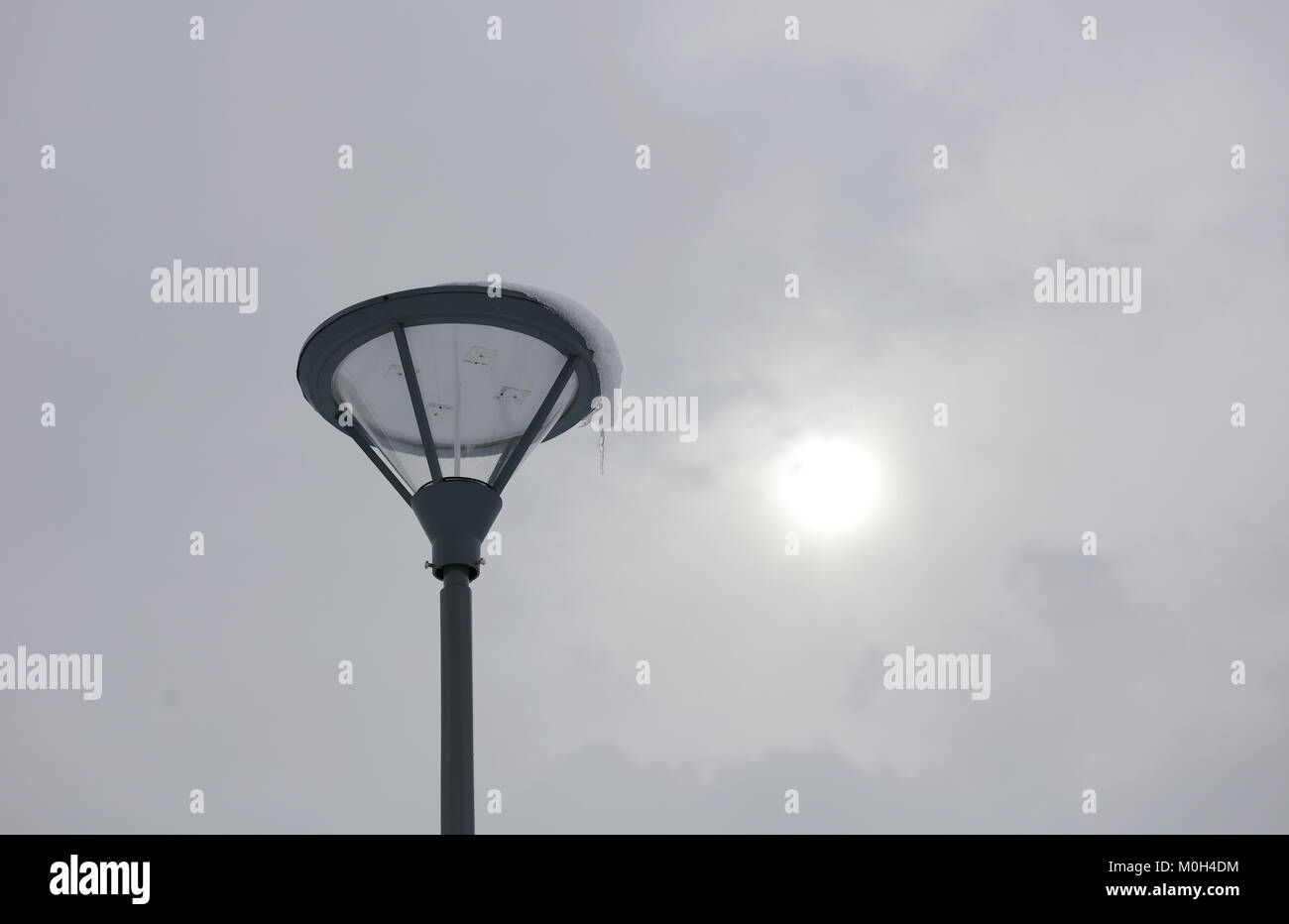 LED street light with grey pole and armature aigainst white winter sky ...