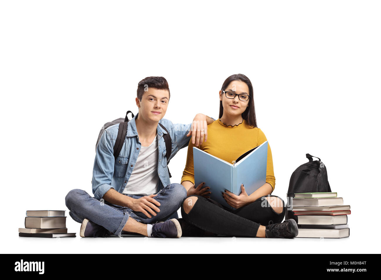 Teen students with books sitting on the floor and looking at the camera ...