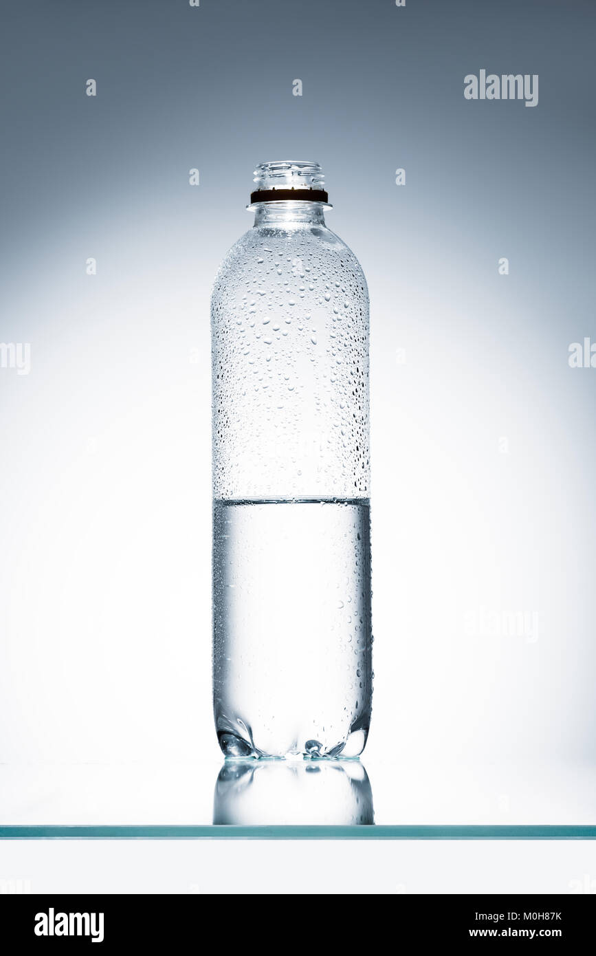 half full plastic bottle of water on reflective surface Stock Photo - Alamy