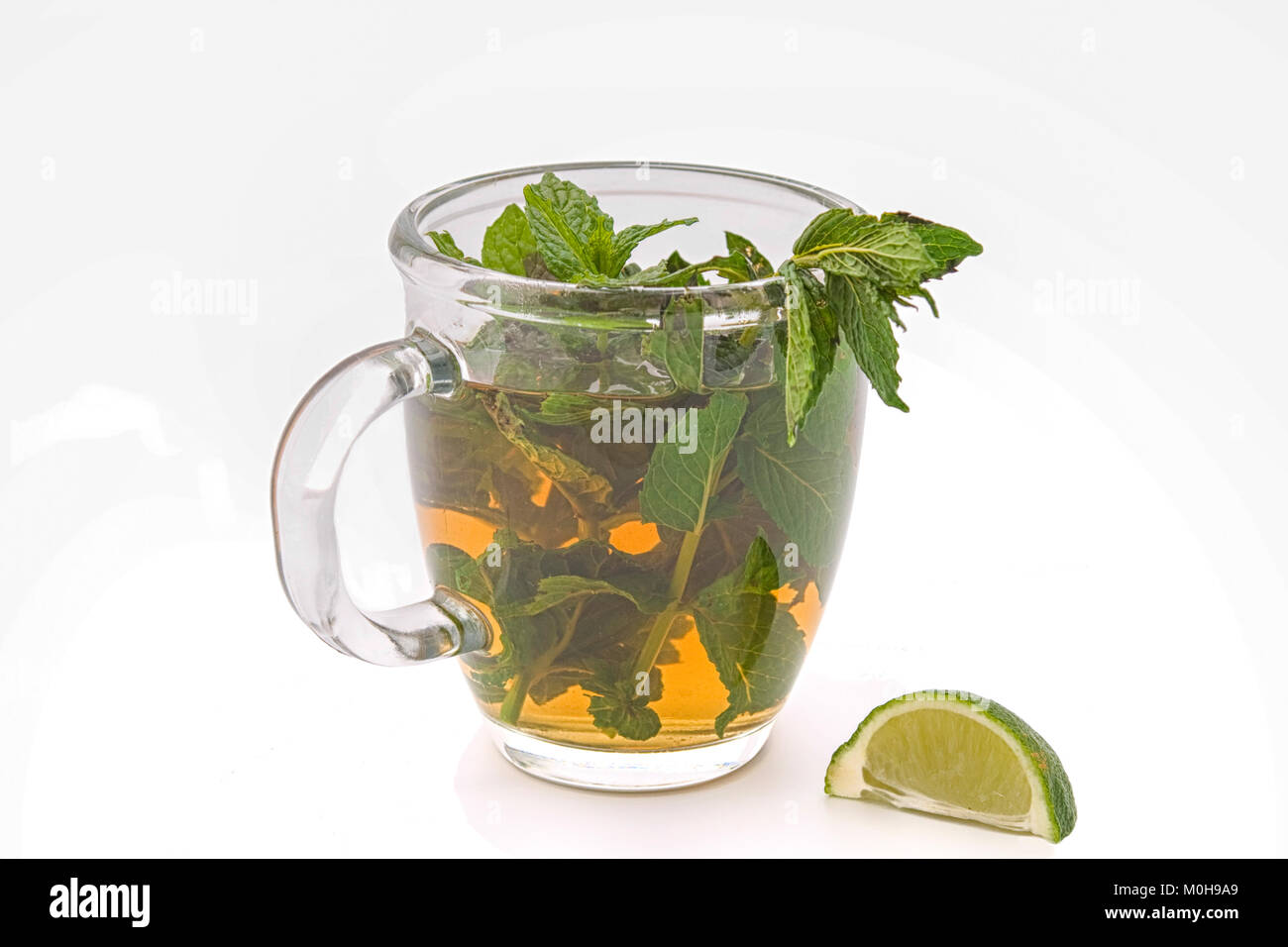 glass with mint tea and lime on white Stock Photo - Alamy