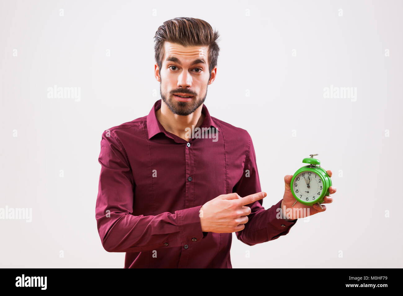 Young businessman is pointing at clock that shows five to twelve time ...