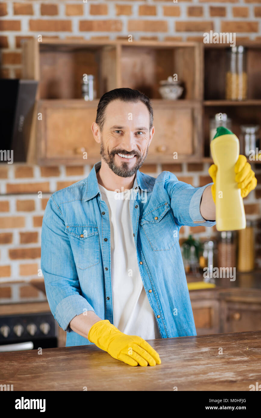 Appealing male cleaner demonstrating cleanser Stock Photo - Alamy