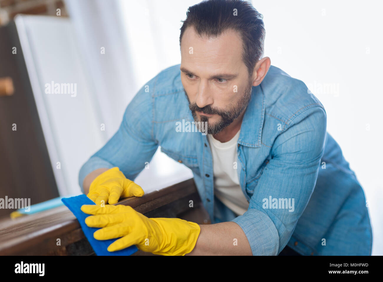 Serious male cleaner wiping out dust Stock Photo - Alamy