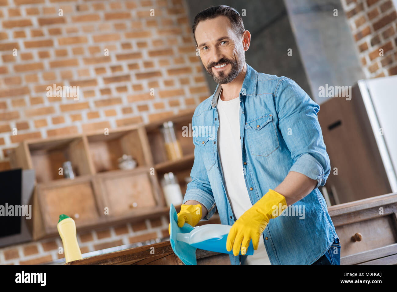 Optimistic male cleaner taking cleanser Stock Photo - Alamy