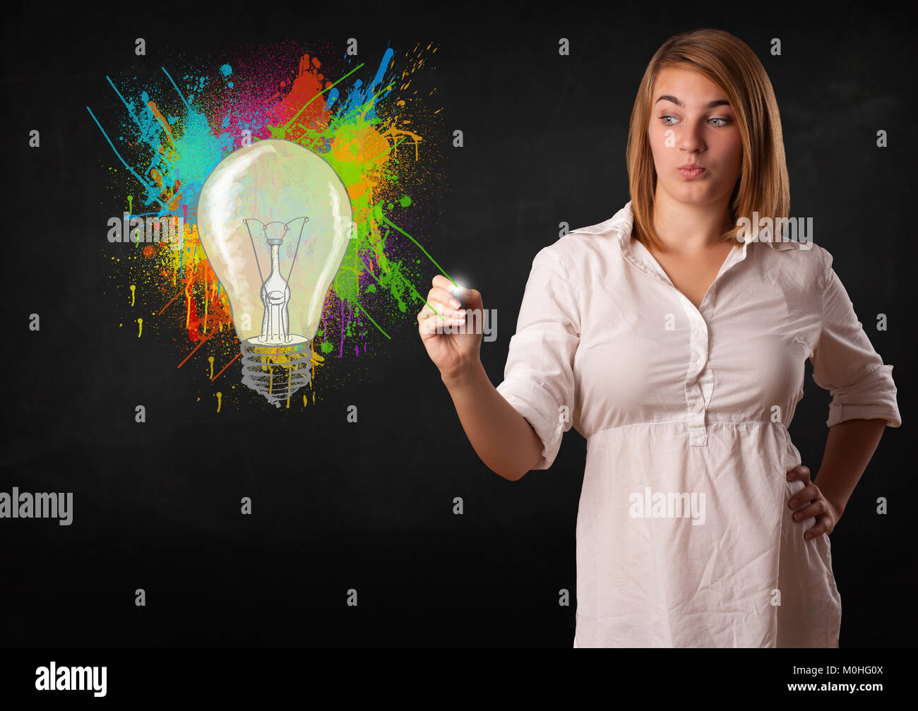Young lady drawing a colorful light bulb with colorful splashes on ...