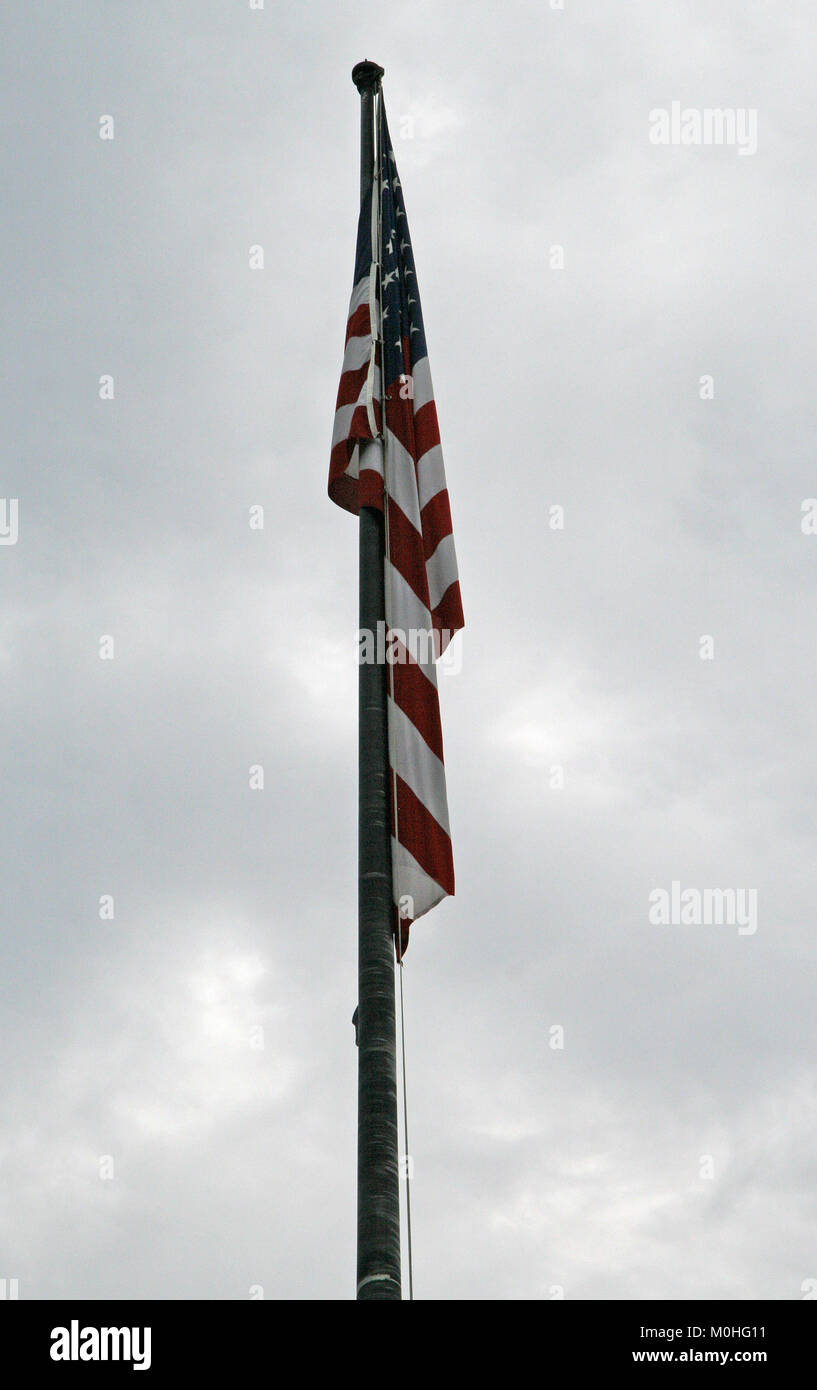 American flag hanging on pole against overcast sky on Liberty Island ...
