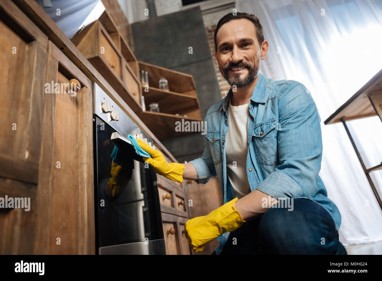Cheerful male cleaner refreshing kitchen Stock Photo - Alamy