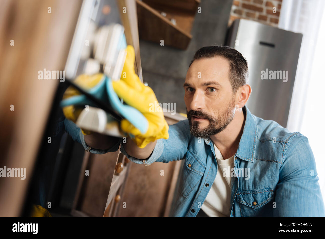 Concentrated male cleaner wiping oven Stock Photo - Alamy