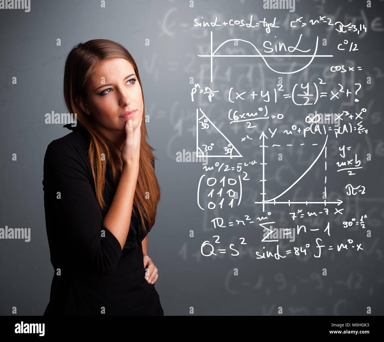 Beautiful young school girl thinking about complex mathematical signs ...