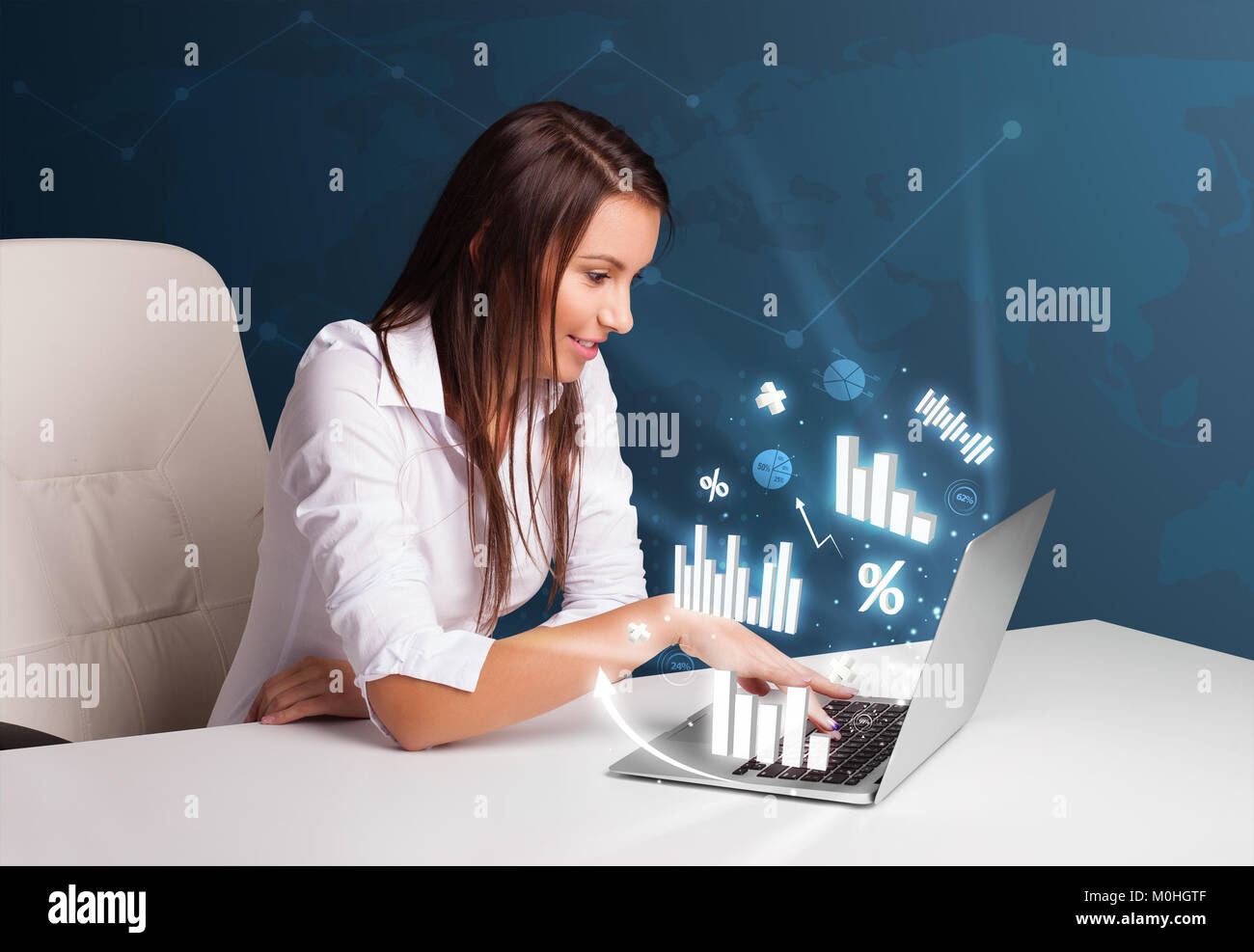Pretty woman sitting at desk and typing on laptop with diagrams and ...
