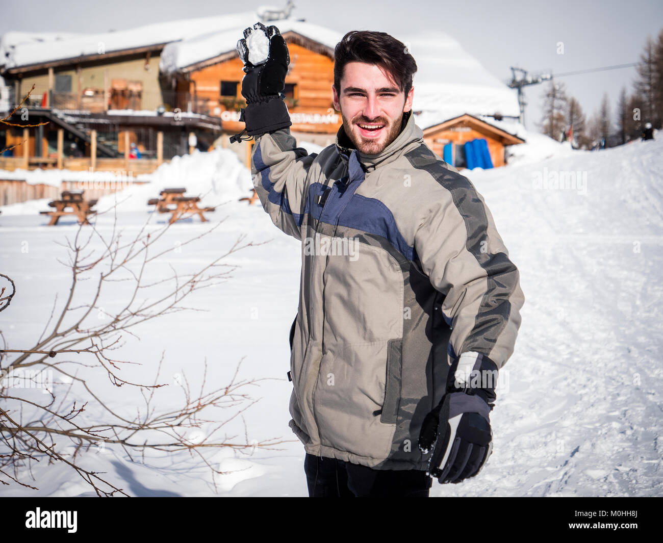 Young man in winter sportswear throwing snowball Stock Photo - Alamy