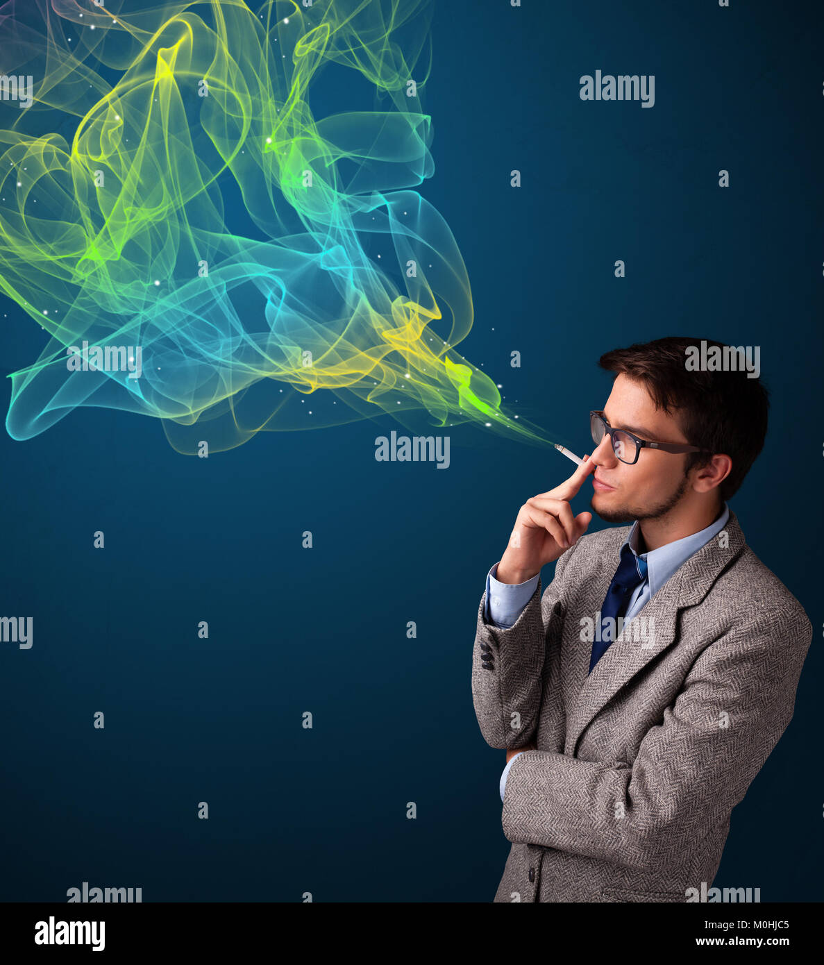 Handsome young man smoking cigarette with colorful smoke Stock Photo ...
