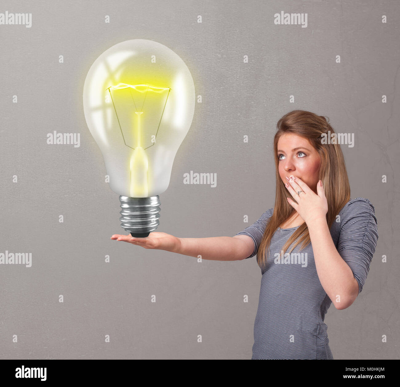 Beautiful young lady holding realistic 3d light bulb Stock Photo - Alamy