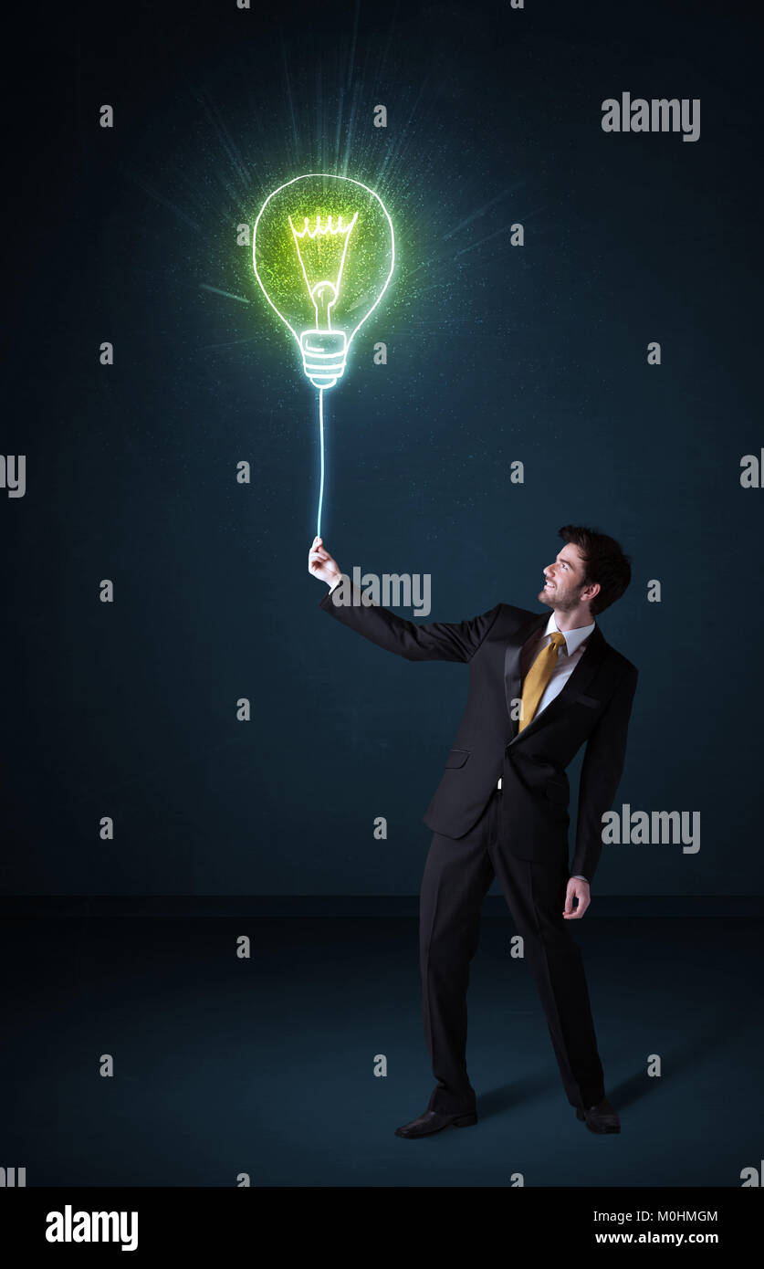 Businessman hold a shining idea bulb on a blue background Stock Photo ...