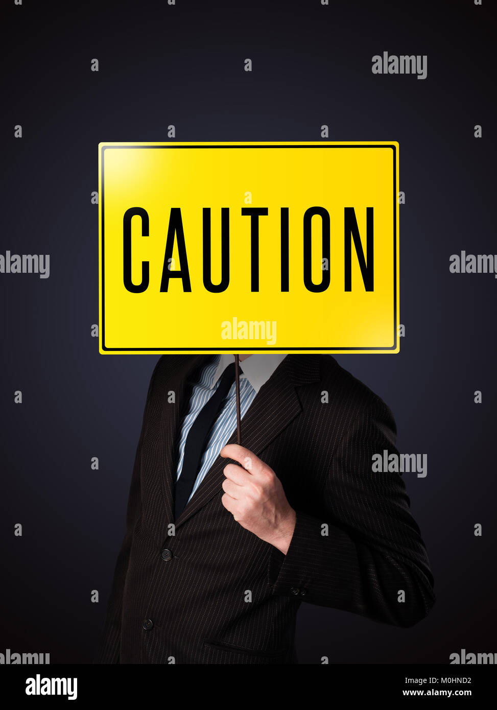 Businessman standing and holding a yellow caution sign in front of his ...
