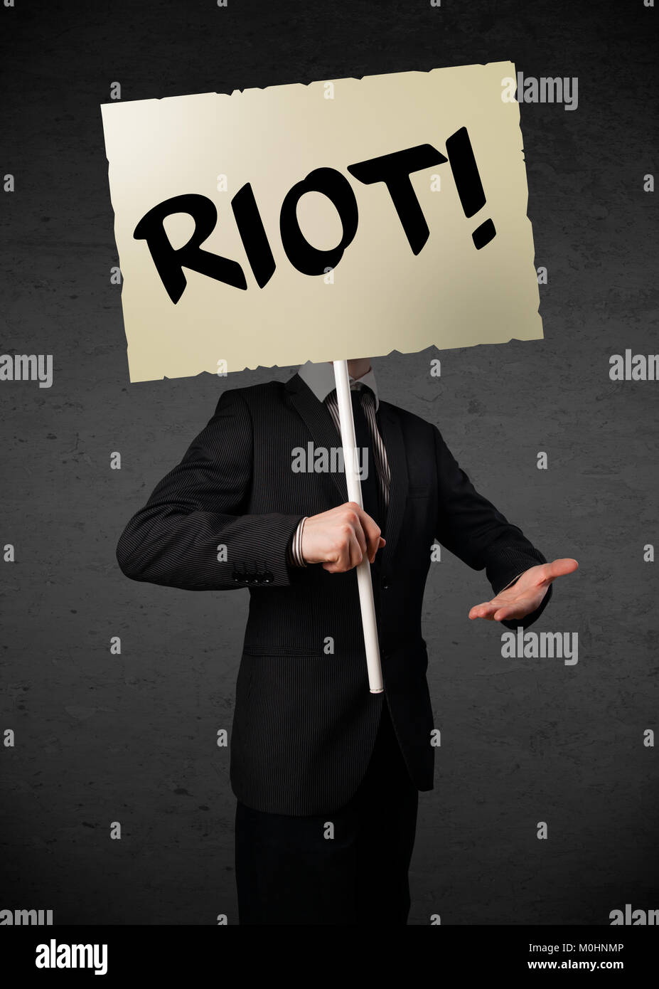 Businessman holding a demonstration board with riot sign in front of ...