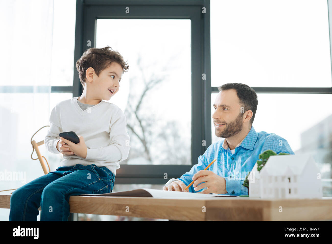 Little boy talking with father while he working on blueprint Stock ...