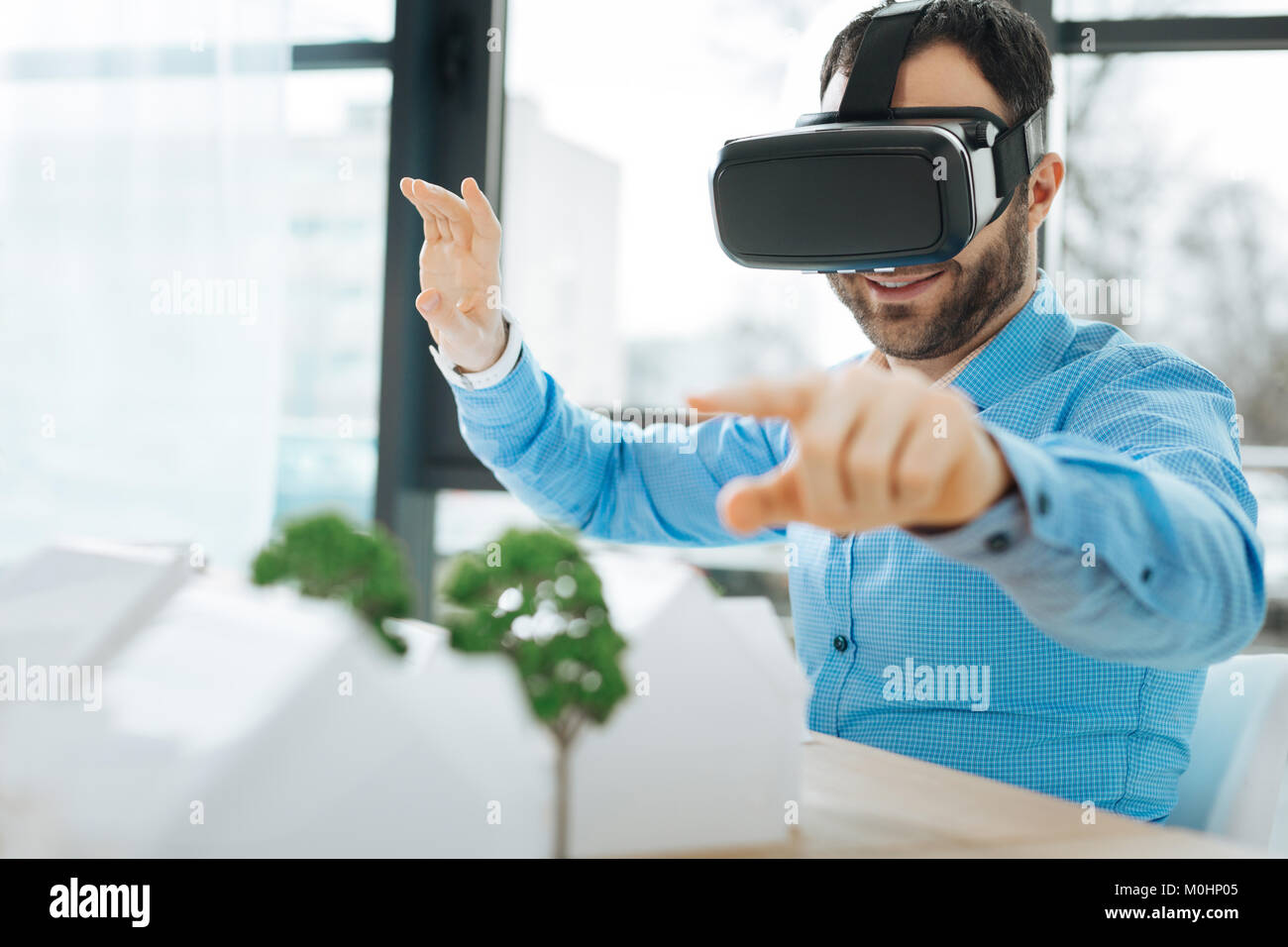 Smiling architect in VR headset pointing at house models Stock Photo ...