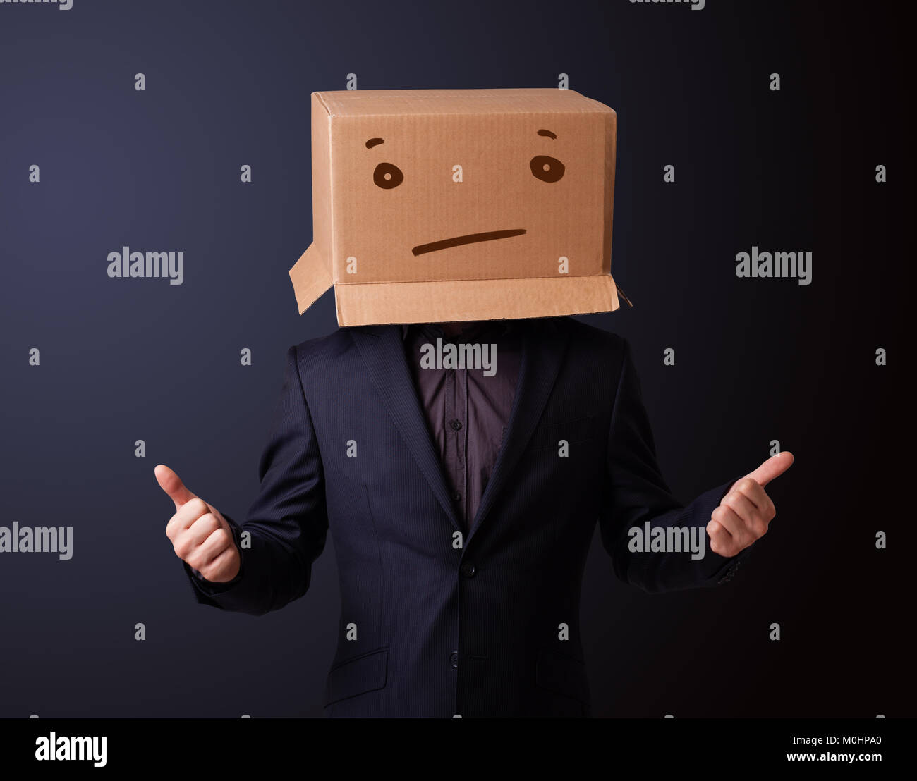 Young man standing and gesturing with a cardboard box on his head with ...