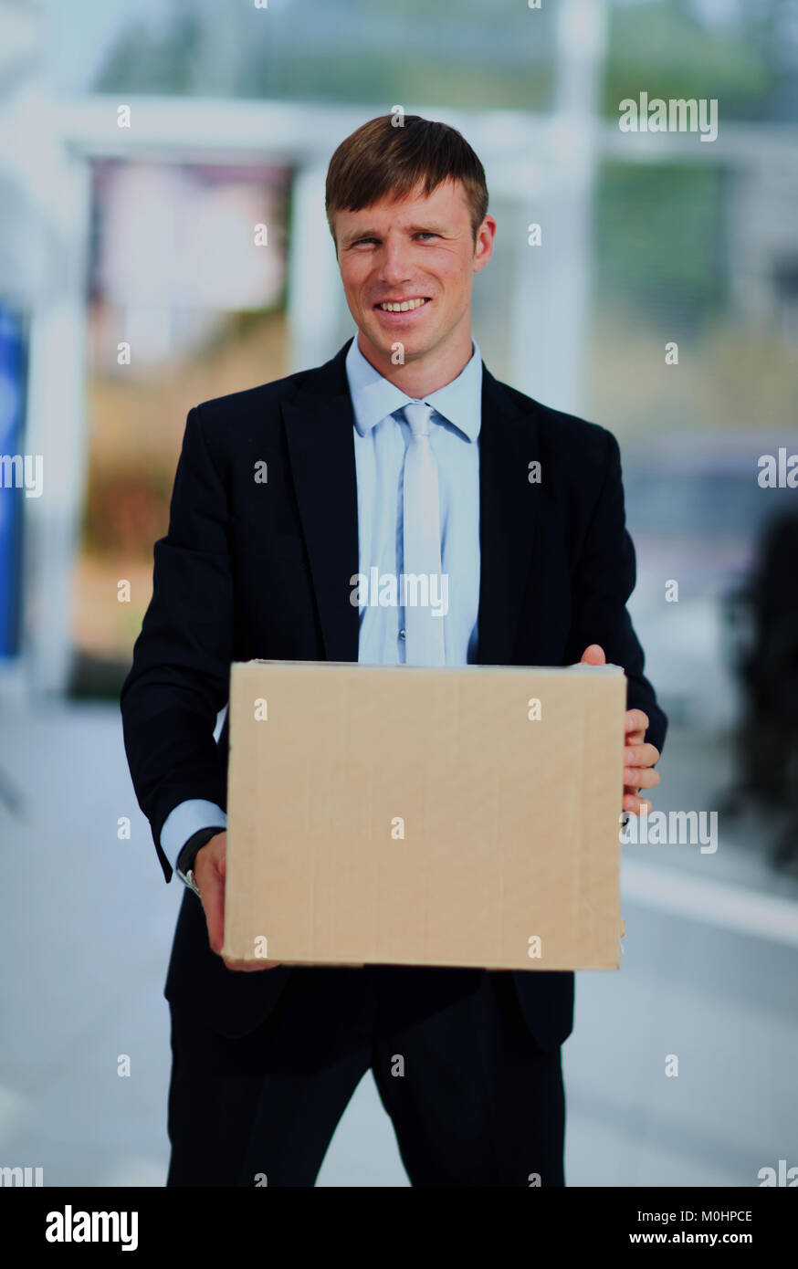 Smiling businessman holding a cardboard box Stock Photo - Alamy