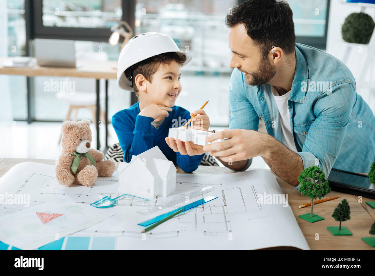 Pleasant father and son examining models in the office Stock Photo - Alamy