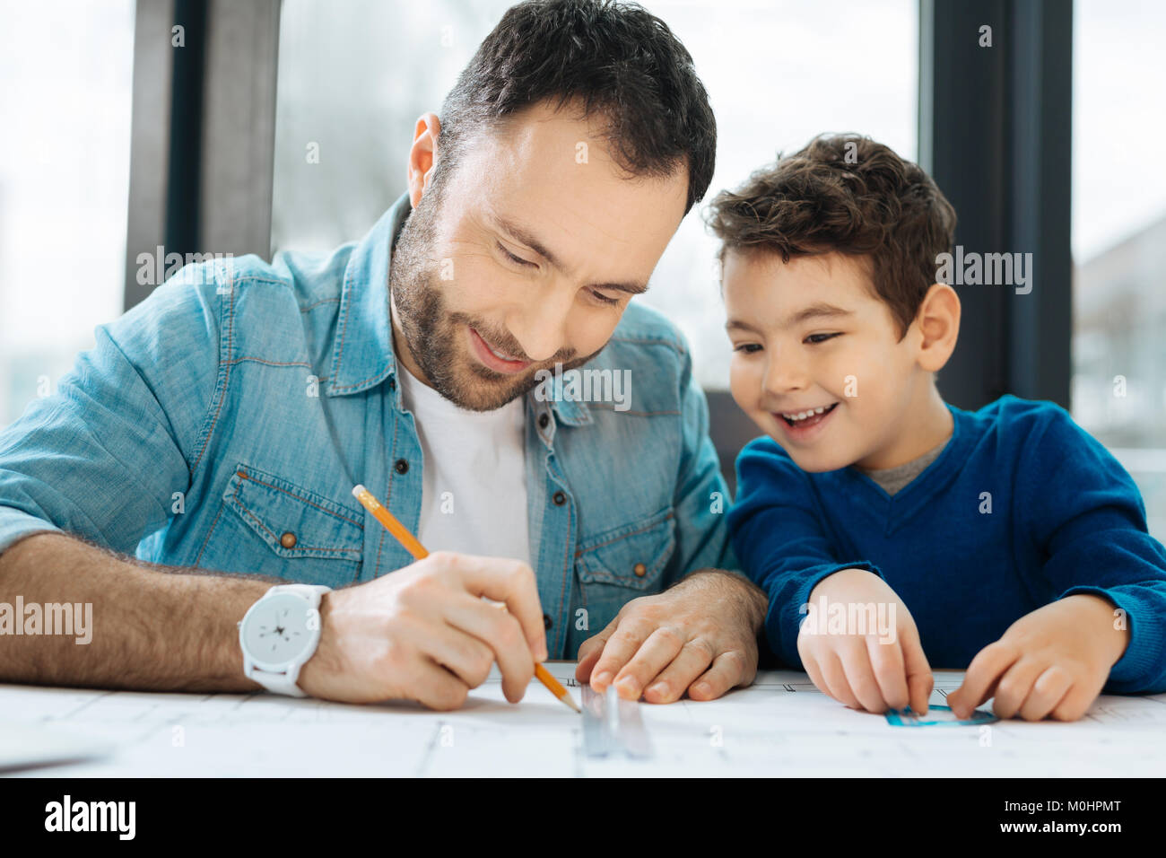 Joyful boy watching his father drawing blueprint Stock Photo - Alamy