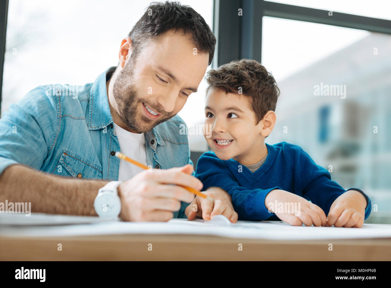 Cheerful kid smiling at father drawing a blueprint Stock Photo - Alamy