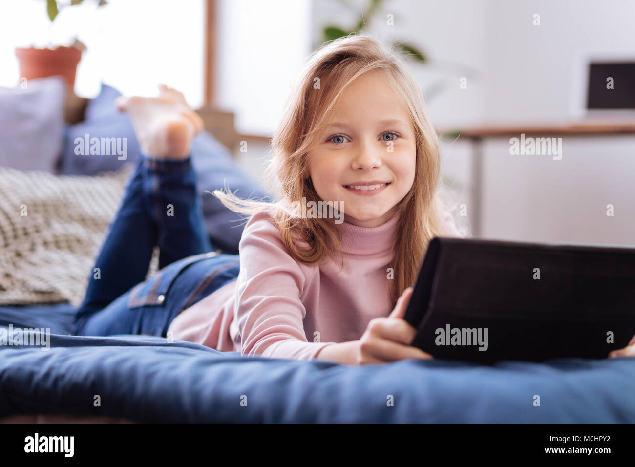 Happy cute girl using her tablet Stock Photo - Alamy