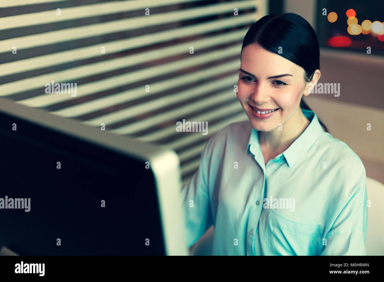 Charming woman sitting in front of computer screen Stock Photo - Alamy