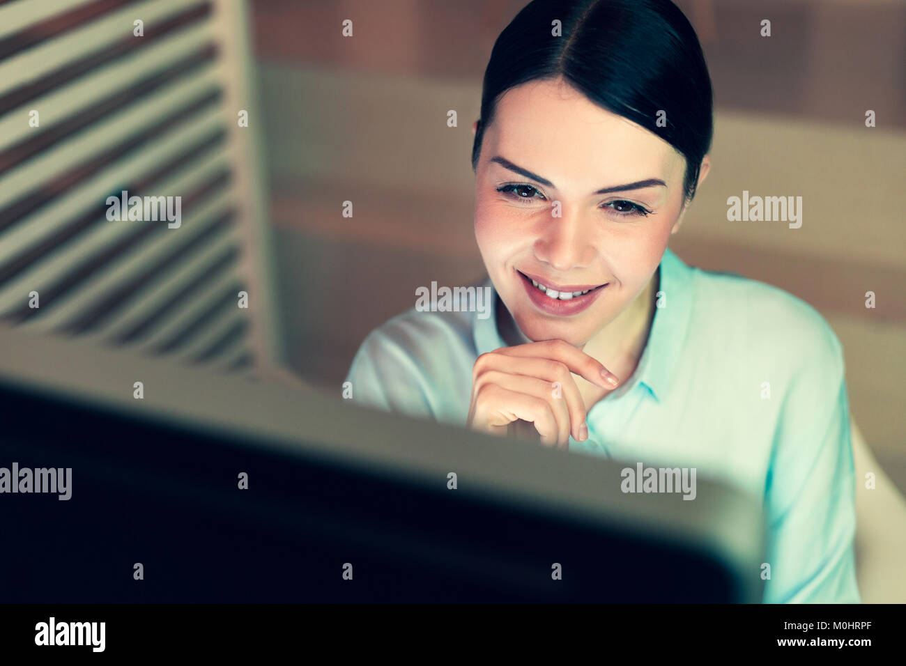 Cheerful woman reading from computer and smiling Stock Photo - Alamy