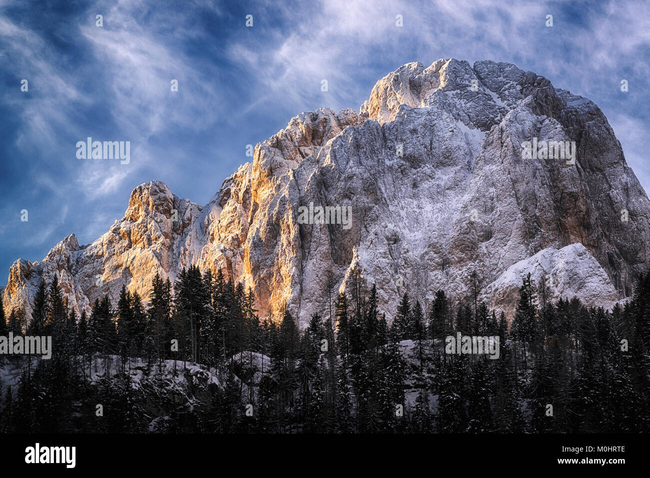 First ray of Sun on the top of mountain Sassolungo in winter morning ...