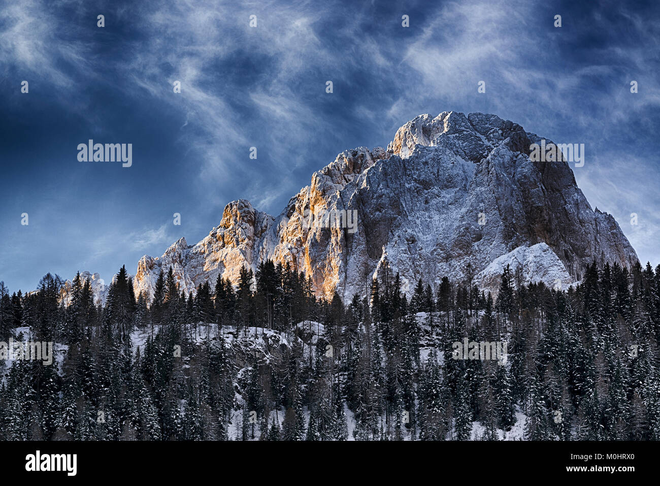 First ray of Sun on the top of mountain Sassolungo in winter morning ...