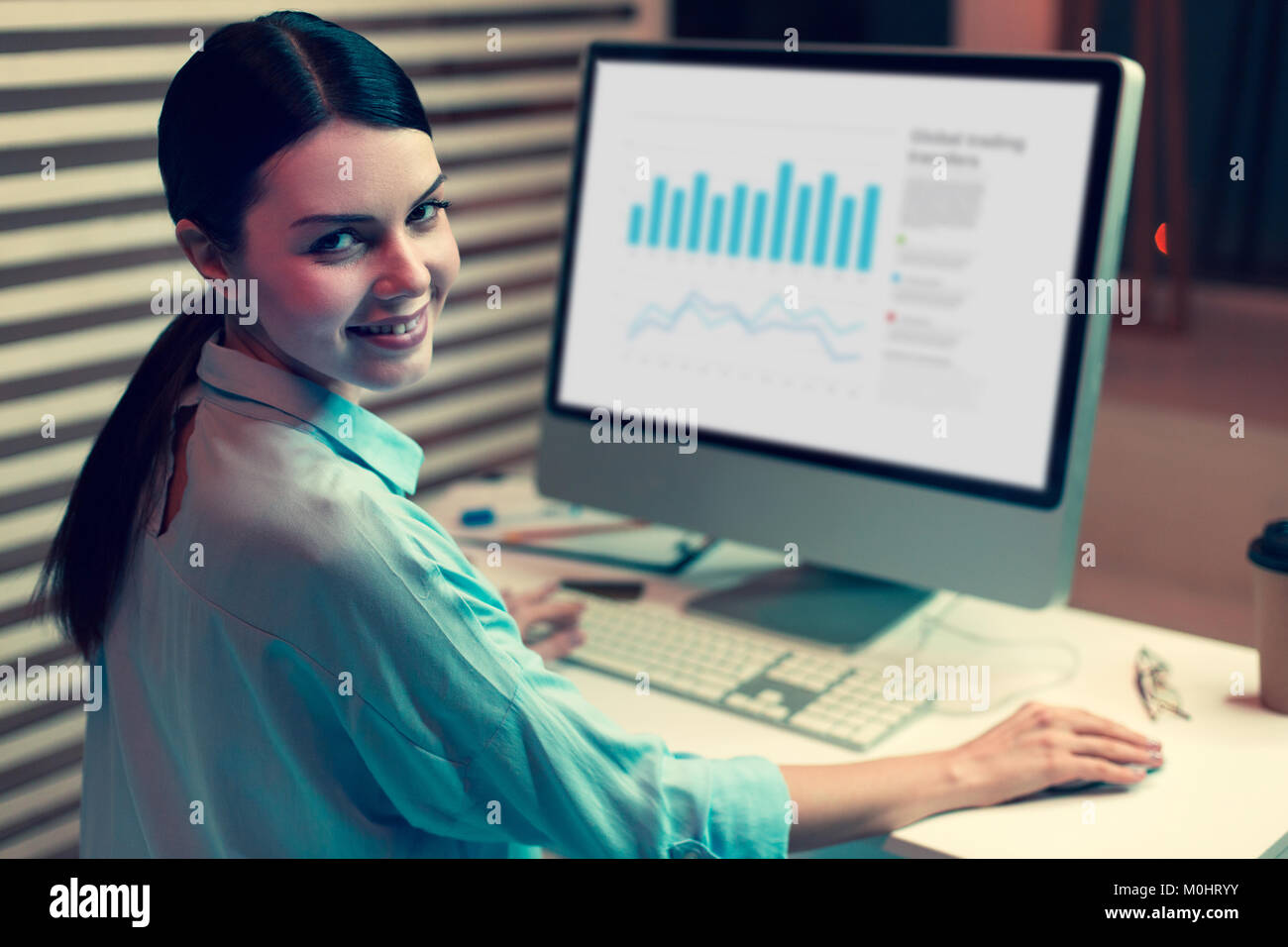 Pretty woman posing while creating graphs on computer Stock Photo - Alamy