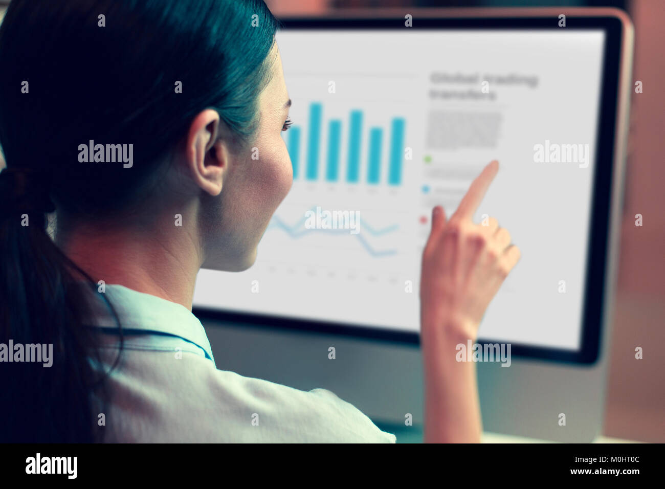 Pretty woman pointing at screen while reading graphs Stock Photo - Alamy