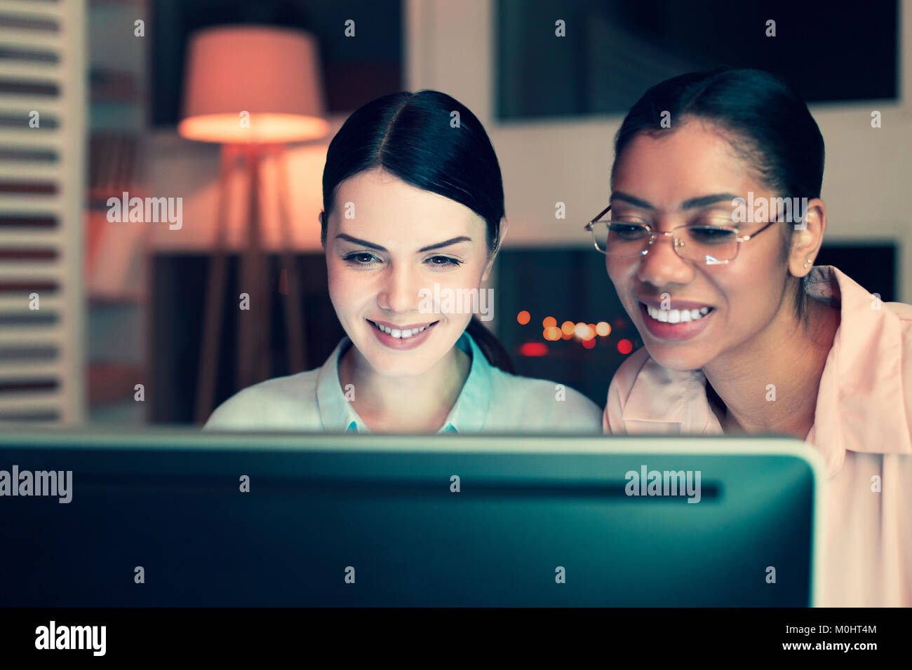 Pretty female colleagues watching video at work Stock Photo - Alamy