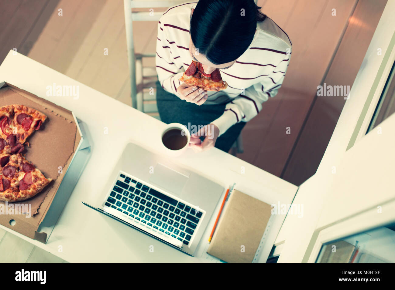 Top view of dark-haired woman eating pizza at workplace Stock Photo - Alamy