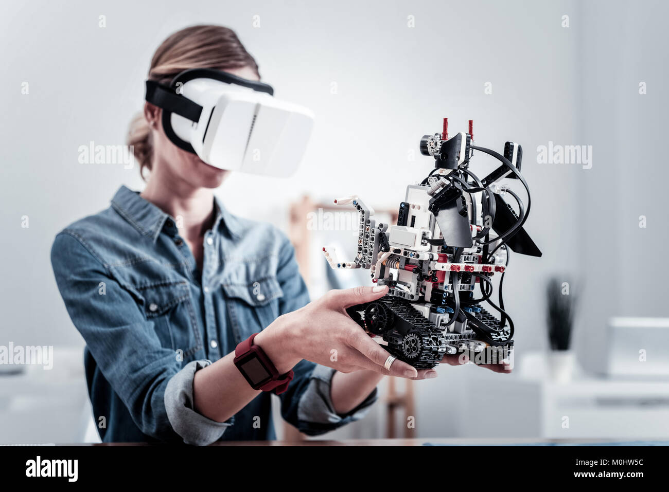 Serious female person examining little robot Stock Photo - Alamy