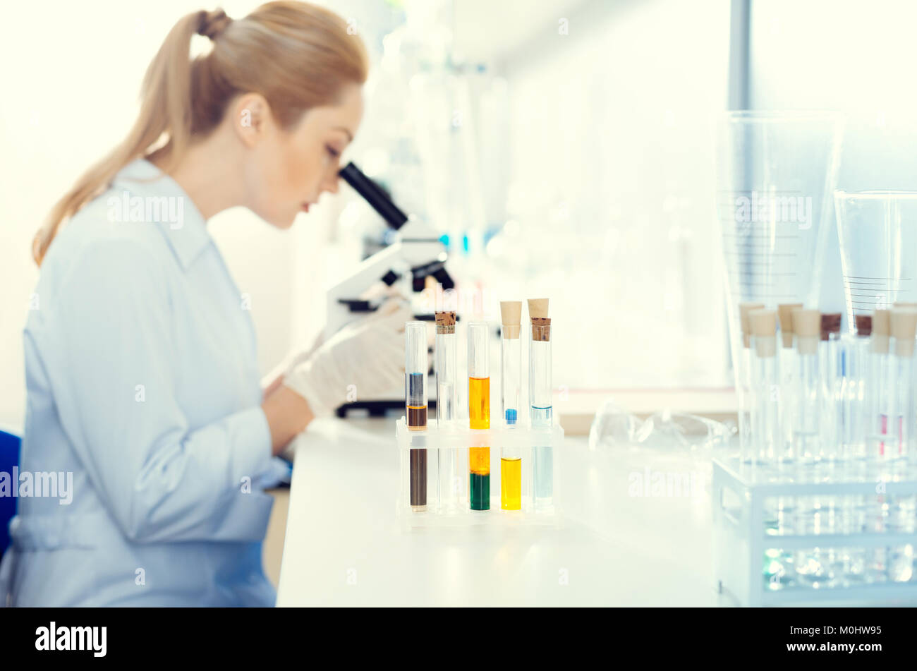 Female lab worker analyzing sample under microscope Stock Photo - Alamy
