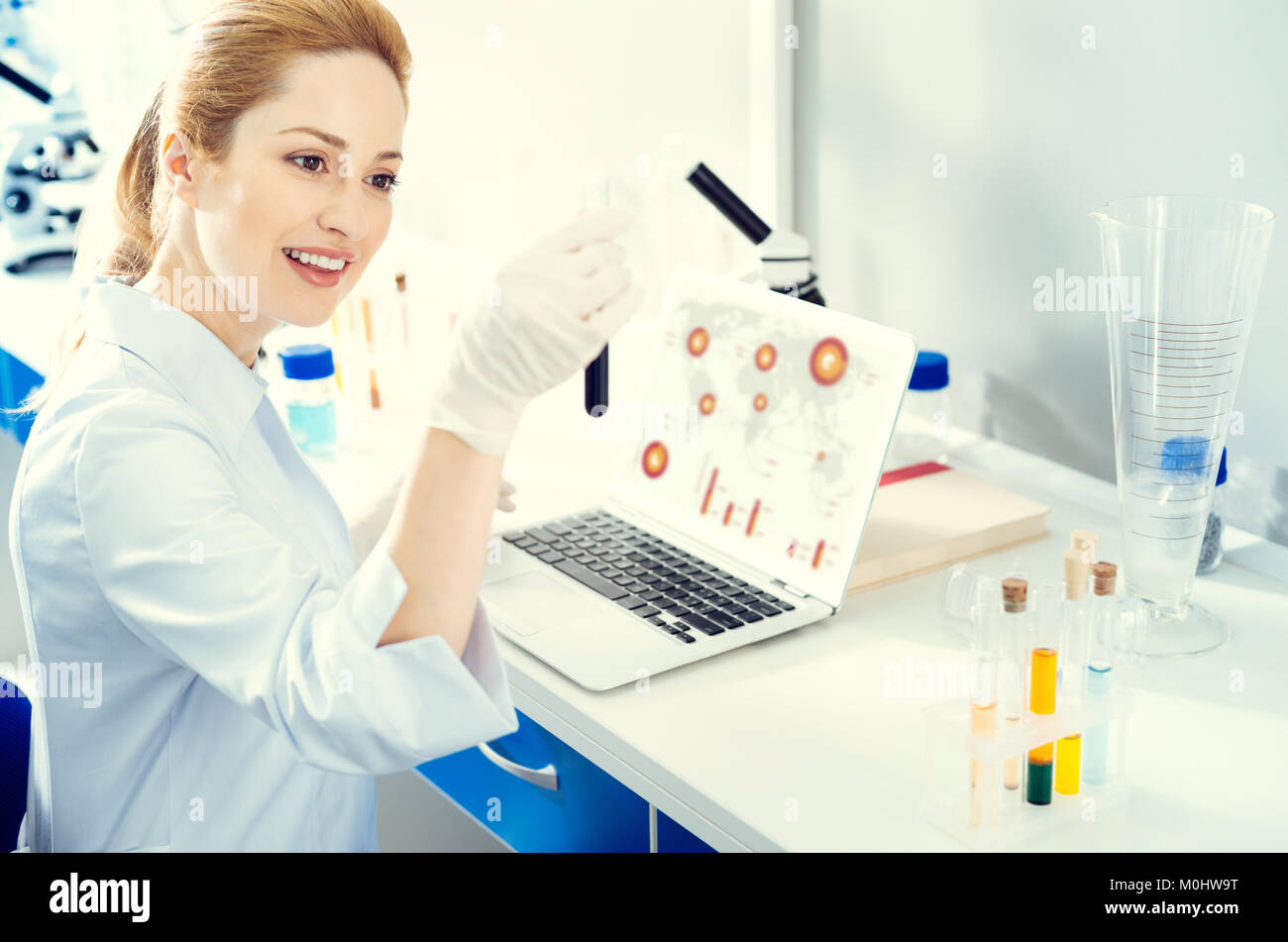 Adult woman analyzing test tube while working in lab Stock Photo - Alamy