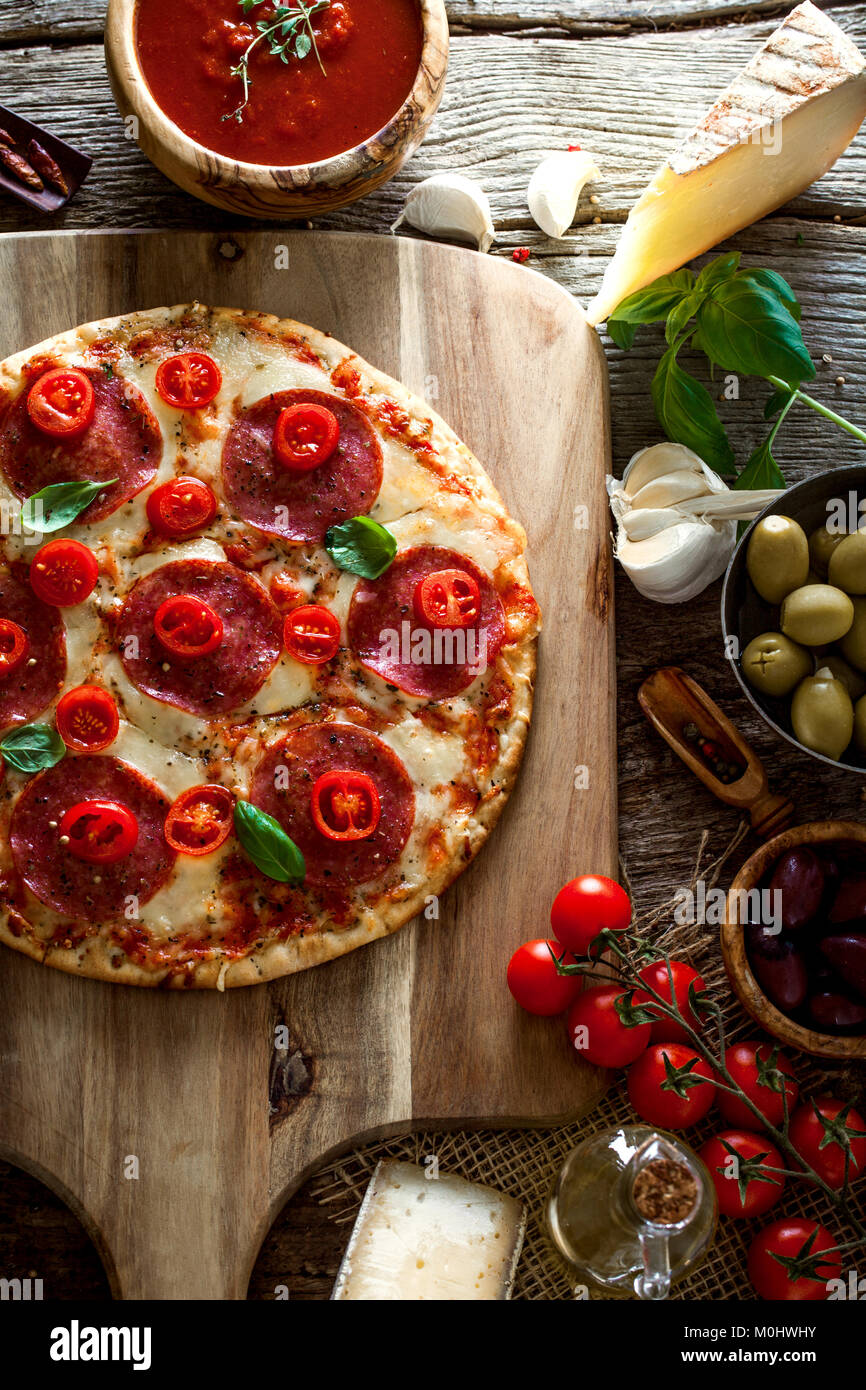 Fresh italian pizza on wood. Pizza with cheese, salami and tomatoes ...