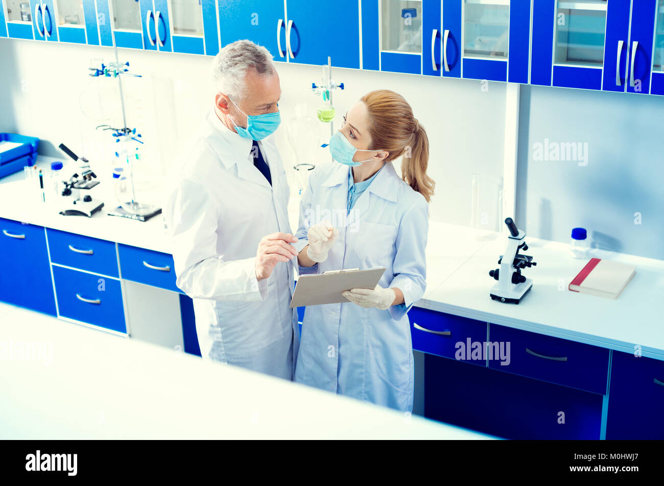 Lab coworkers consulting and taking notes Stock Photo - Alamy