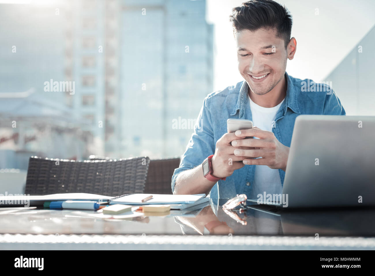 Smiling student using smartphone while doing homework Stock Photo - Alamy