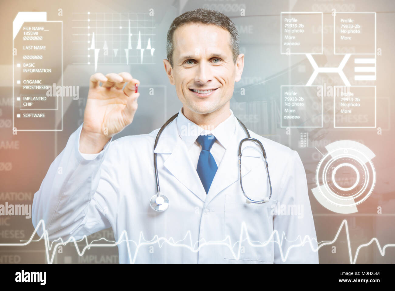 Positive doctor smiling cheerfully while holding a red pill in his hand ...