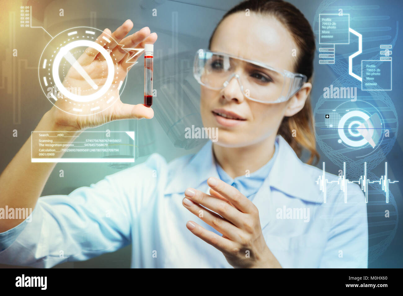 Thoughtful hematologist looking attentively at the blood sample in her ...