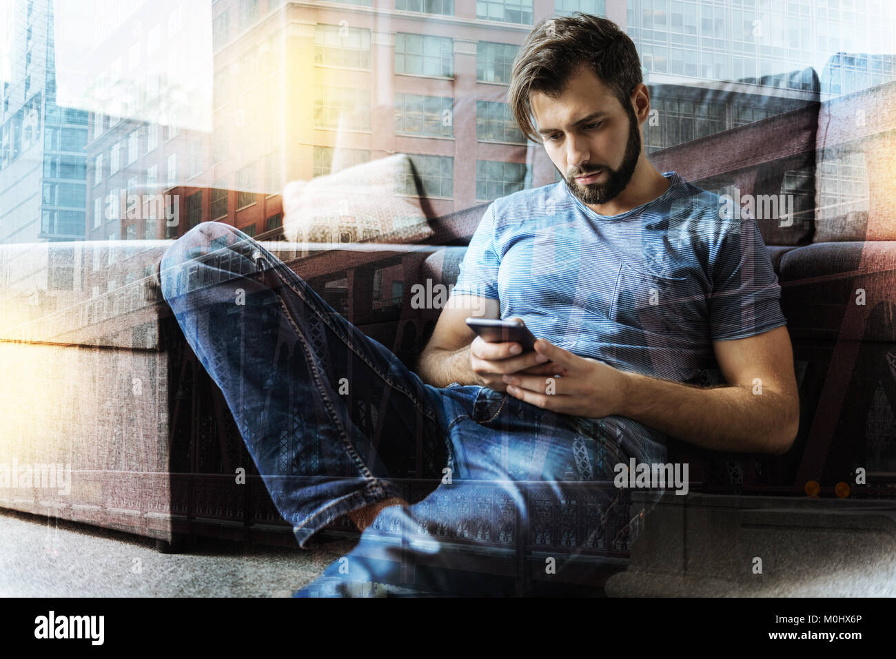 Young man reading messages while sitting on the floor Stock Photo - Alamy