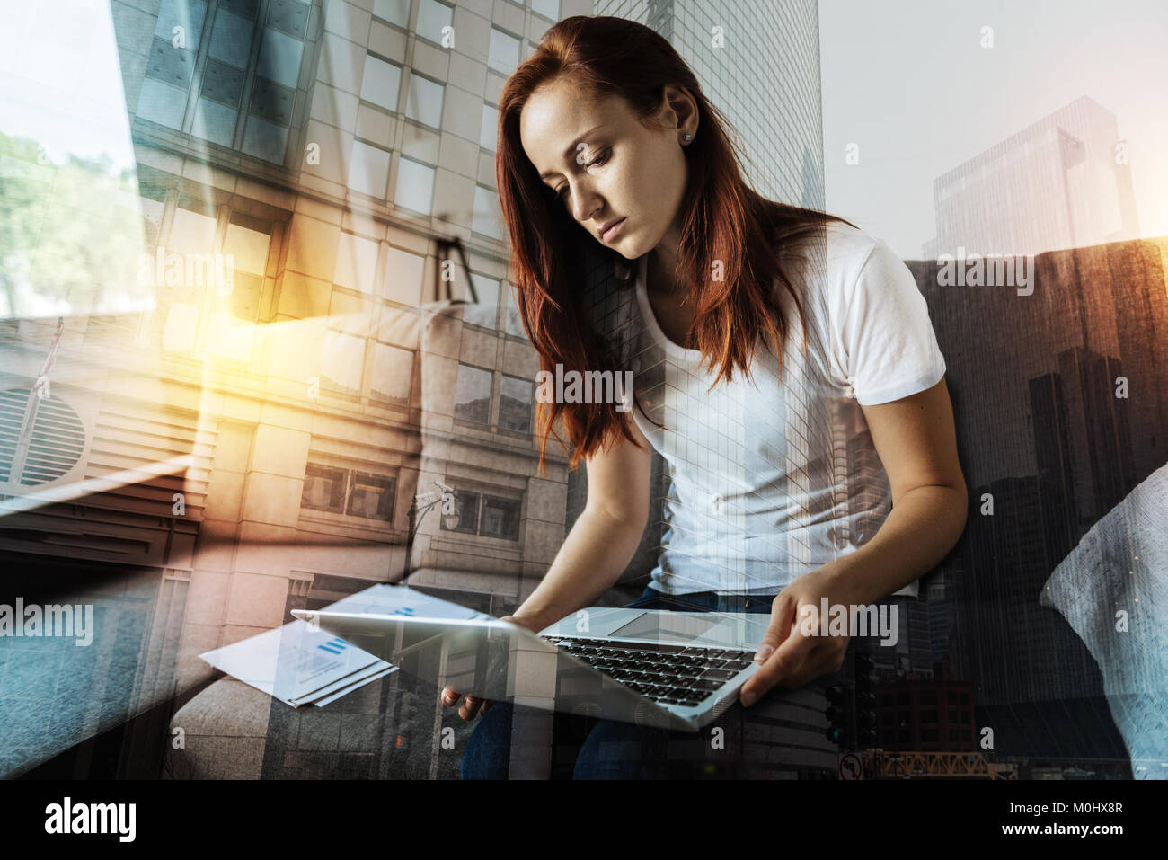 Serious woman sitting with a laptop and looking at the screen Stock ...