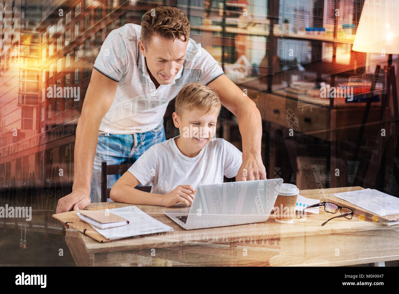 Attentive father pointing to the screen while helping his son with ...