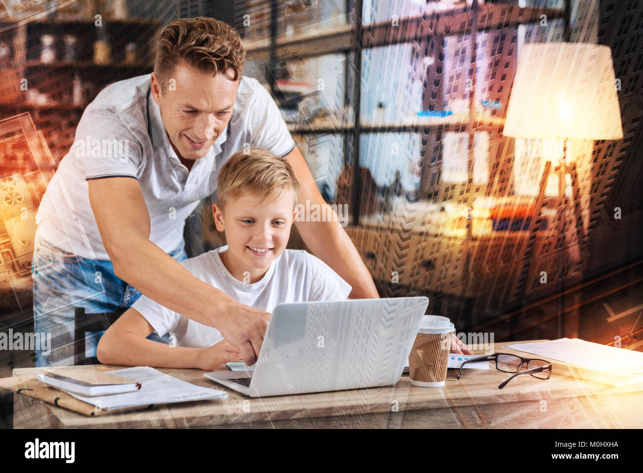 Kind father pointing to the screen while standing near his smiling son ...