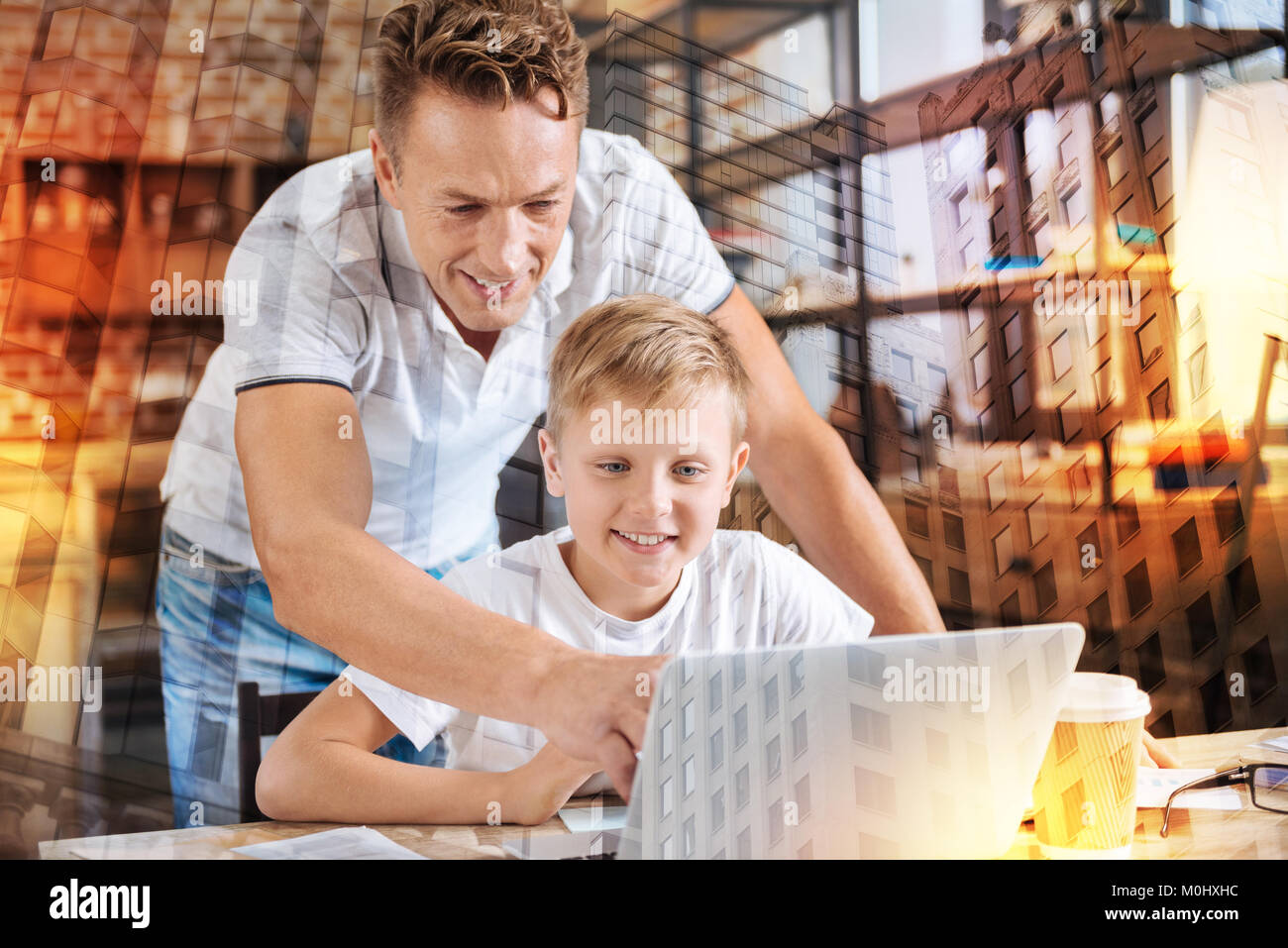 Positive father and son looking at the screen of their modern laptop ...