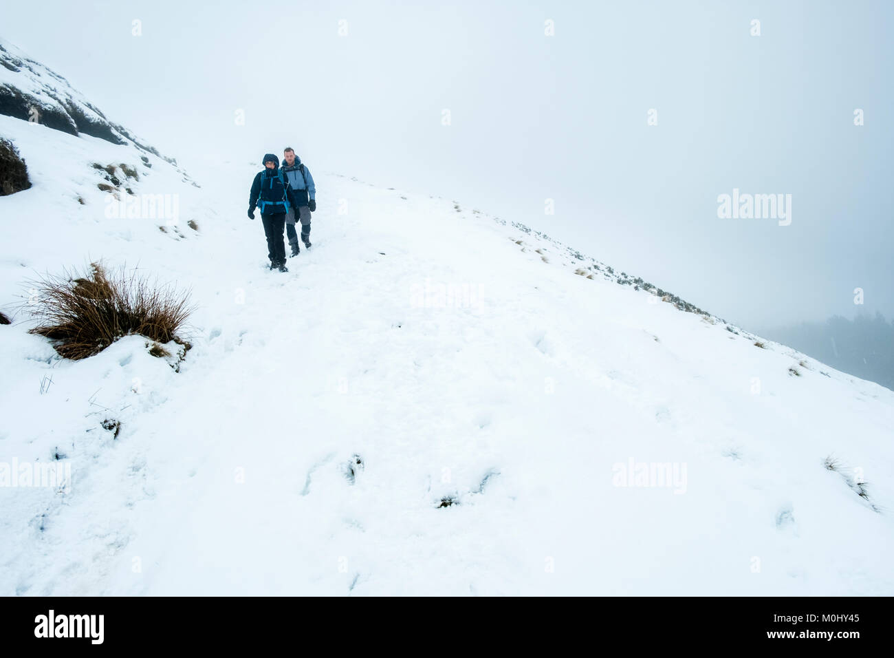 Hiking in Winter. Walkers in snow walking down a path from Kinder Scout ...